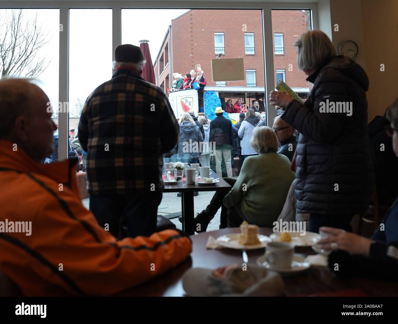 Marne, Germany. 03rd Mar, 2025. Guests in a café follow a float during ...