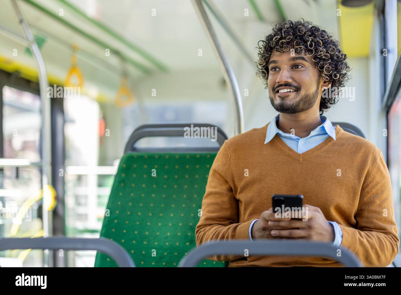 Happy man with phone in hands rides in public transport, passenger ...