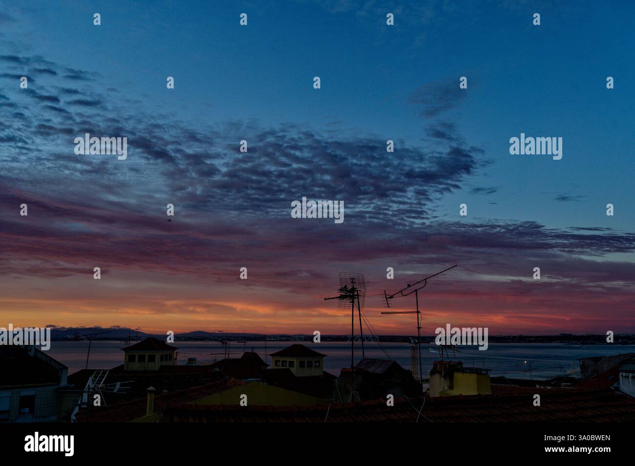 A mesmerizing sunset over Lisbon’s rooftops, where warm hues meet the ...