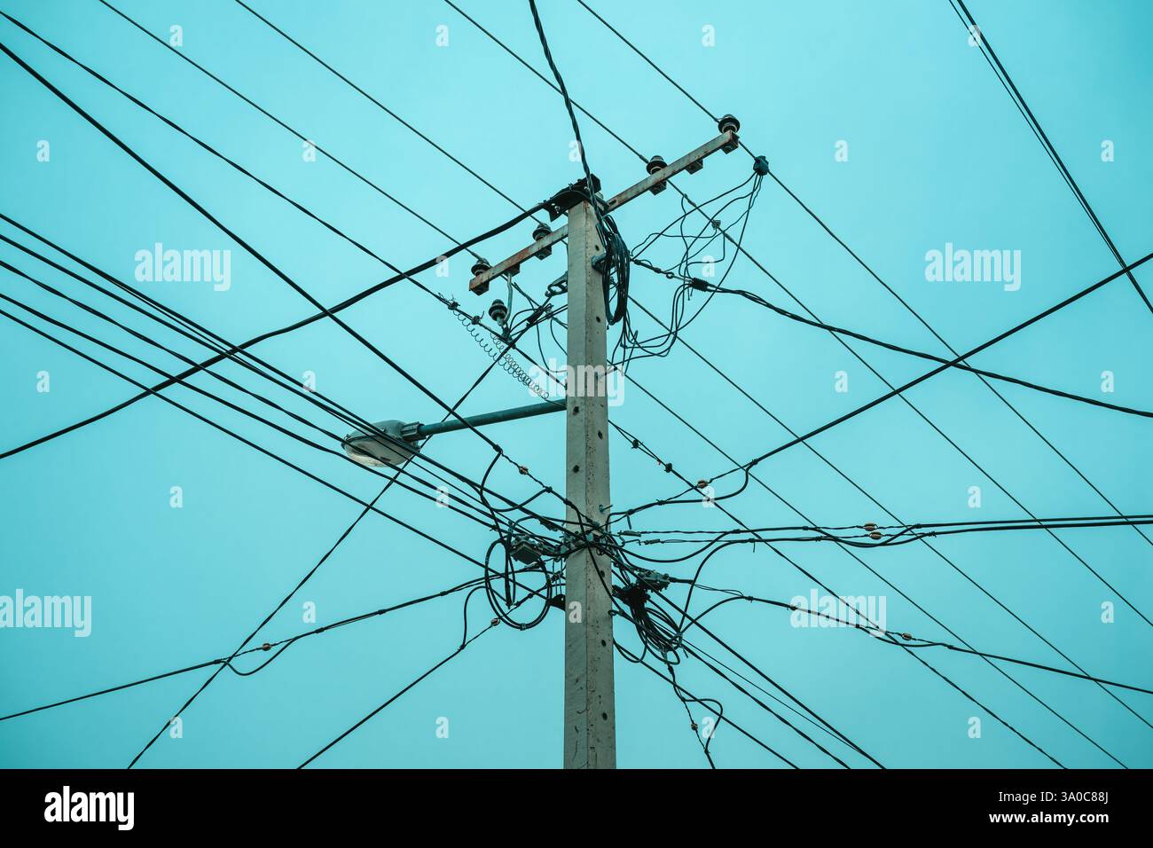 Old concrete lamp post with street light and messy electrical wires ...