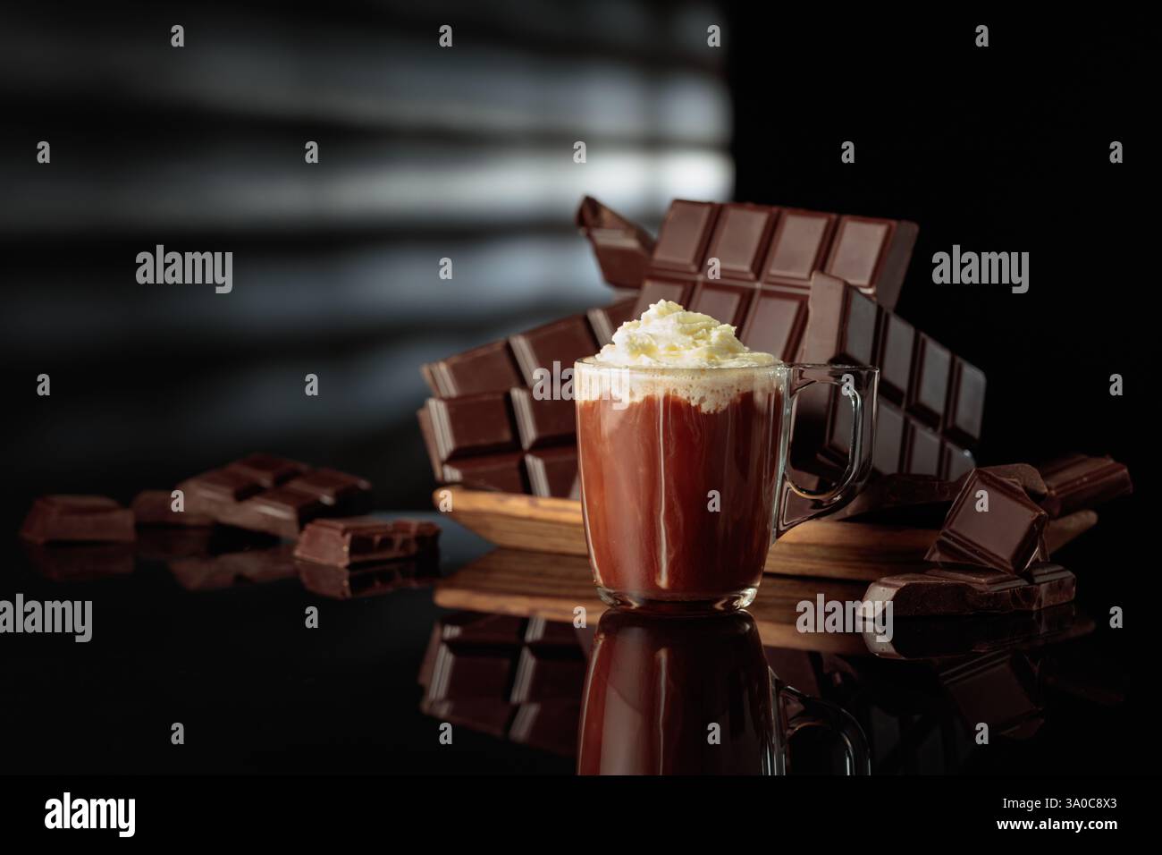 A mug of hot chocolate with airy whipped cream against broken bitter ...