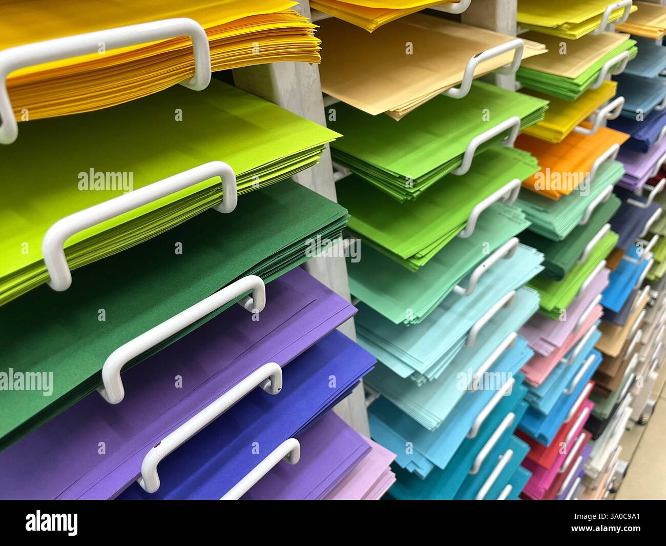 Colorful paper sheets are neatly stacked and arranged on shelves ...