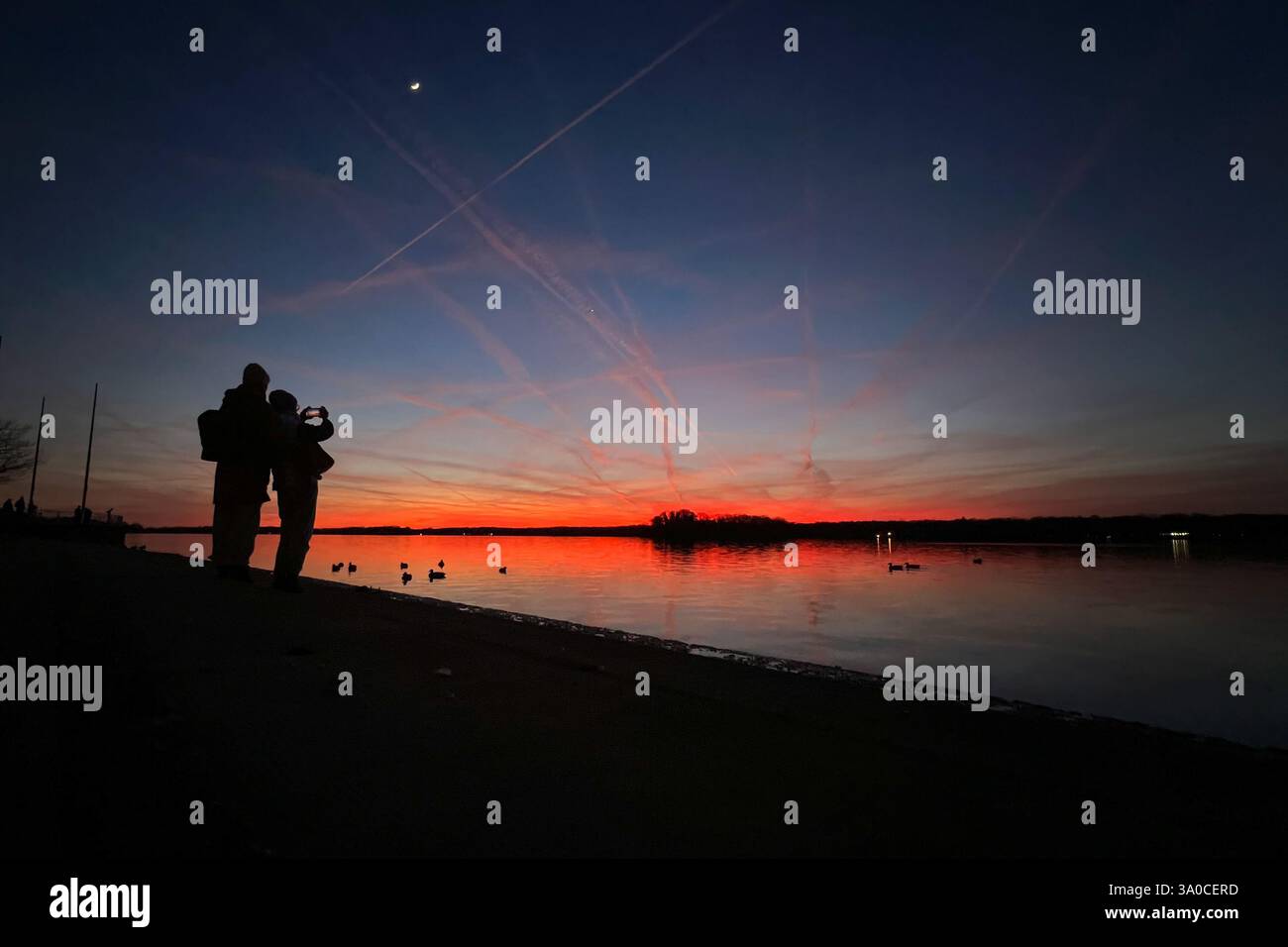Berlin, Germany. 03rd Mar, 2025. A couple stands by Lake Tegel shortly after sunset. Credit ...