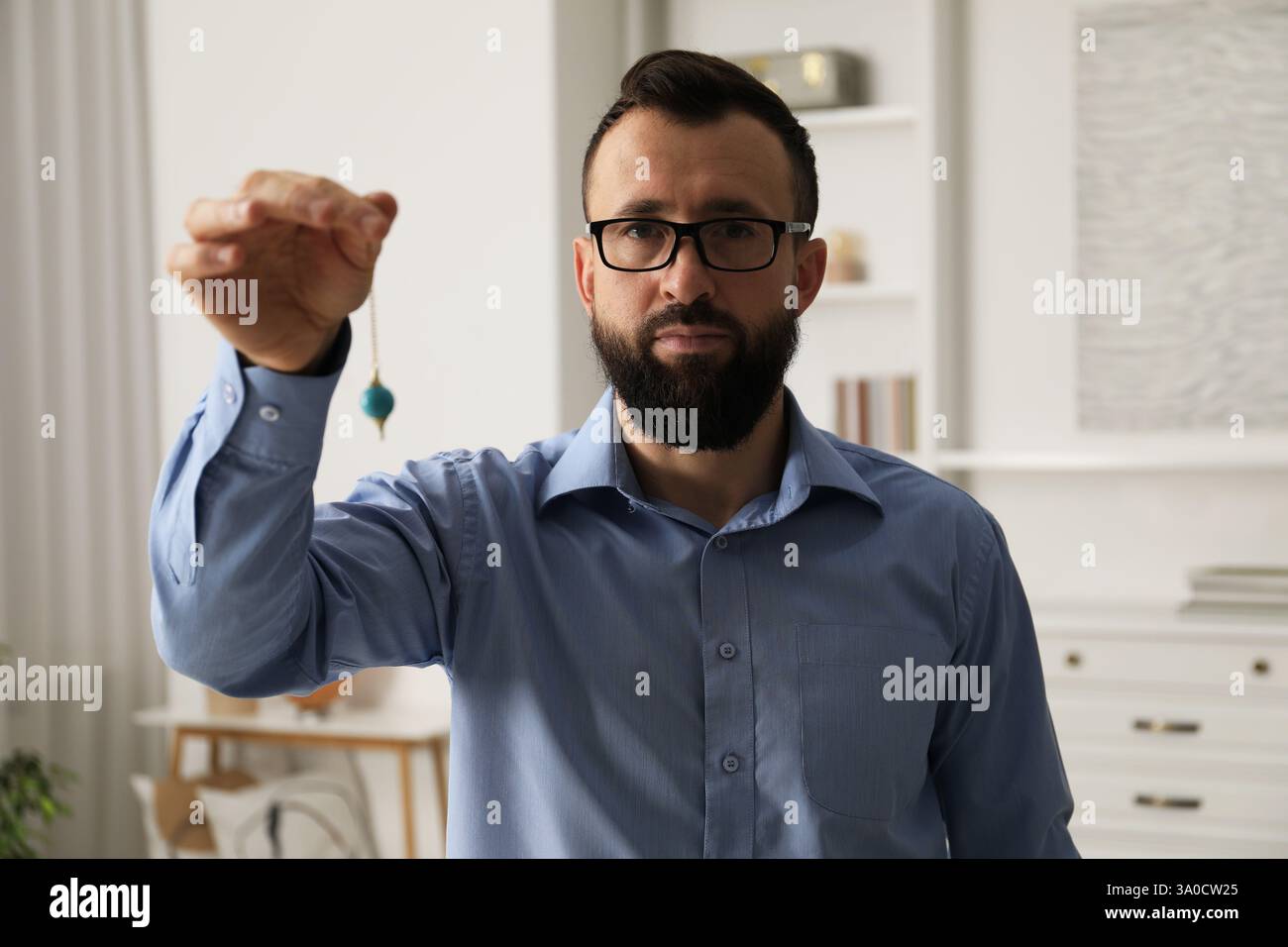 Hypnosis session. Man in glasses swinging pendulum indoors Stock Photo ...