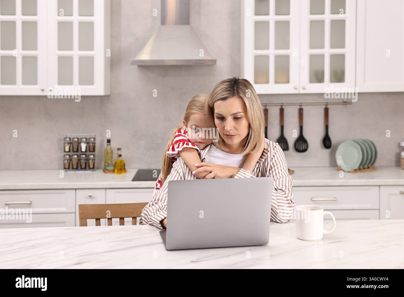 Work-family balance. Single mother working with laptop and her daughter ...