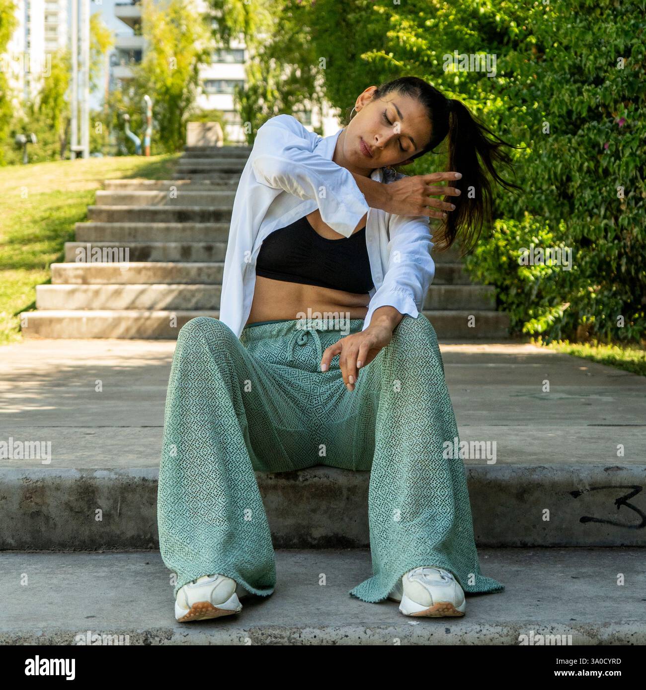 Urban dancer showcasing seated dance moves in a city park Stock Photo ...