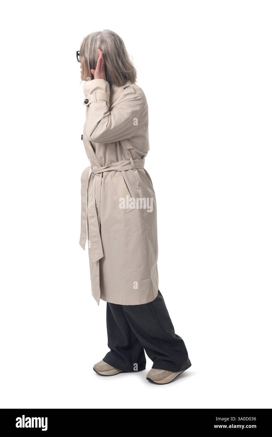 side view of a woman with hand on ear who is listening on white ...