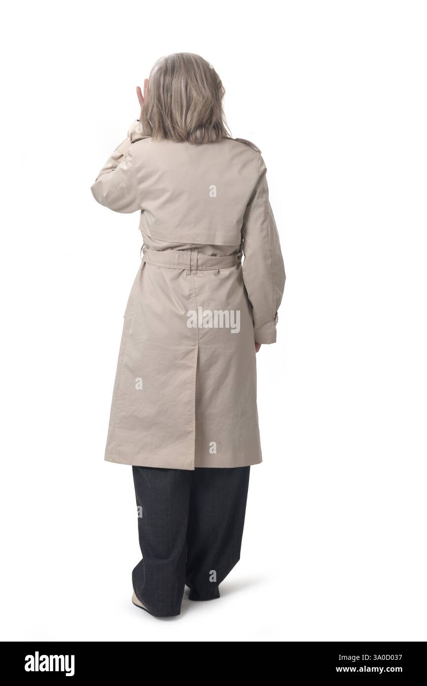 back view of a woman with hand on ear who is listening on white ...