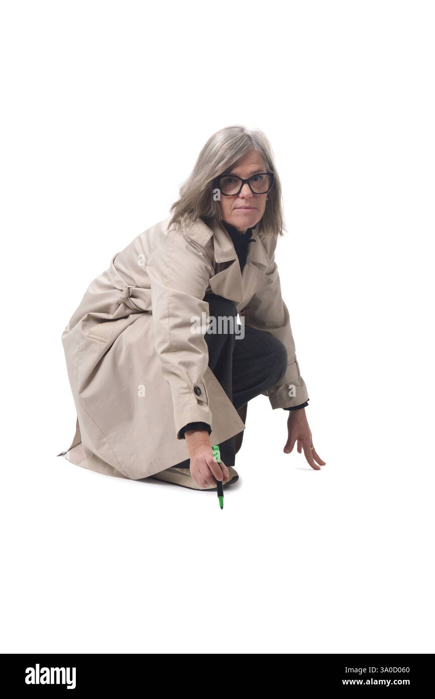 woman squatting who is drawing with a marker on the floor on white ...