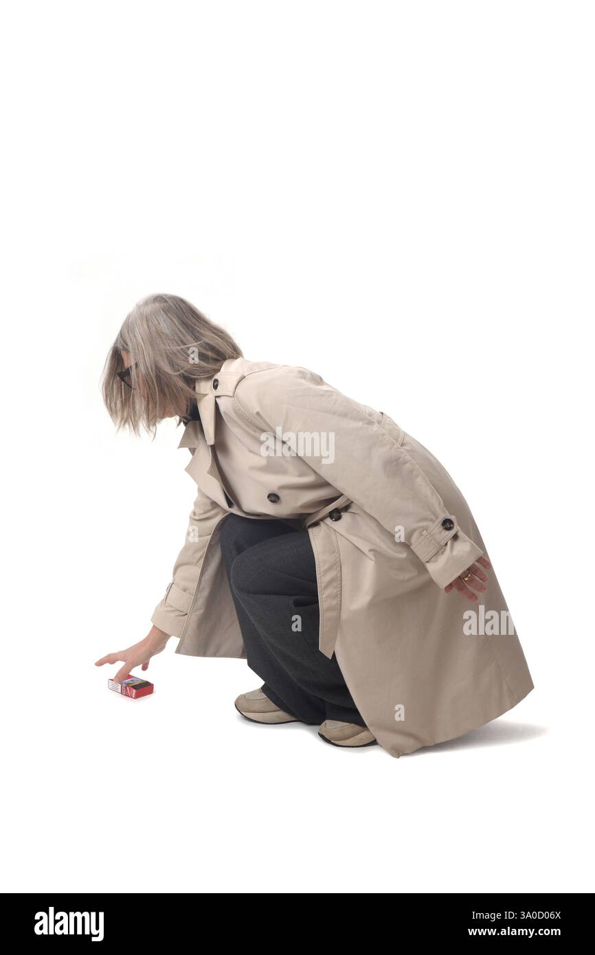 side view of a woman picking up a cigarette pack on the floor on white ...