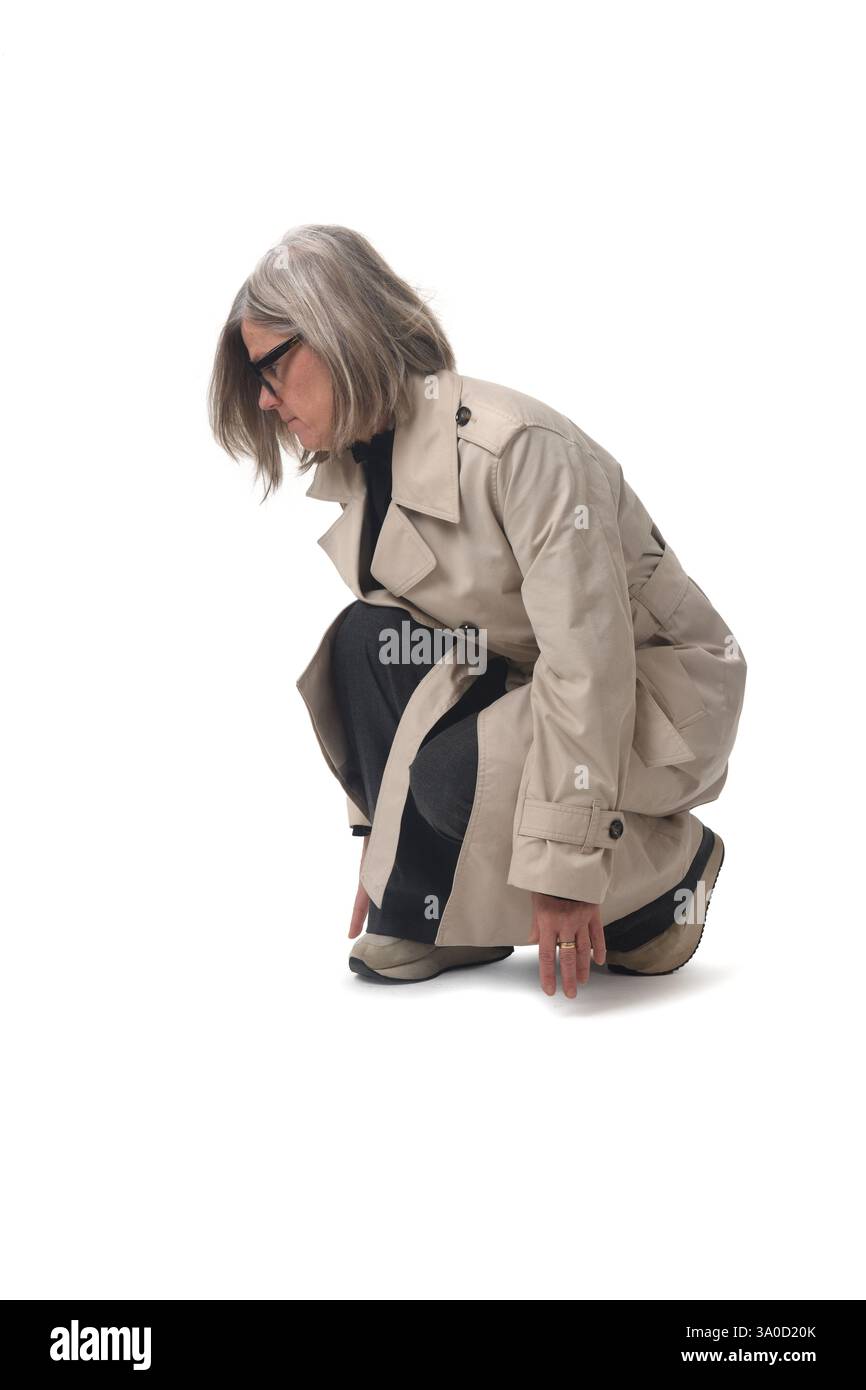 side view o f a woman squatting and looking down on white background ...