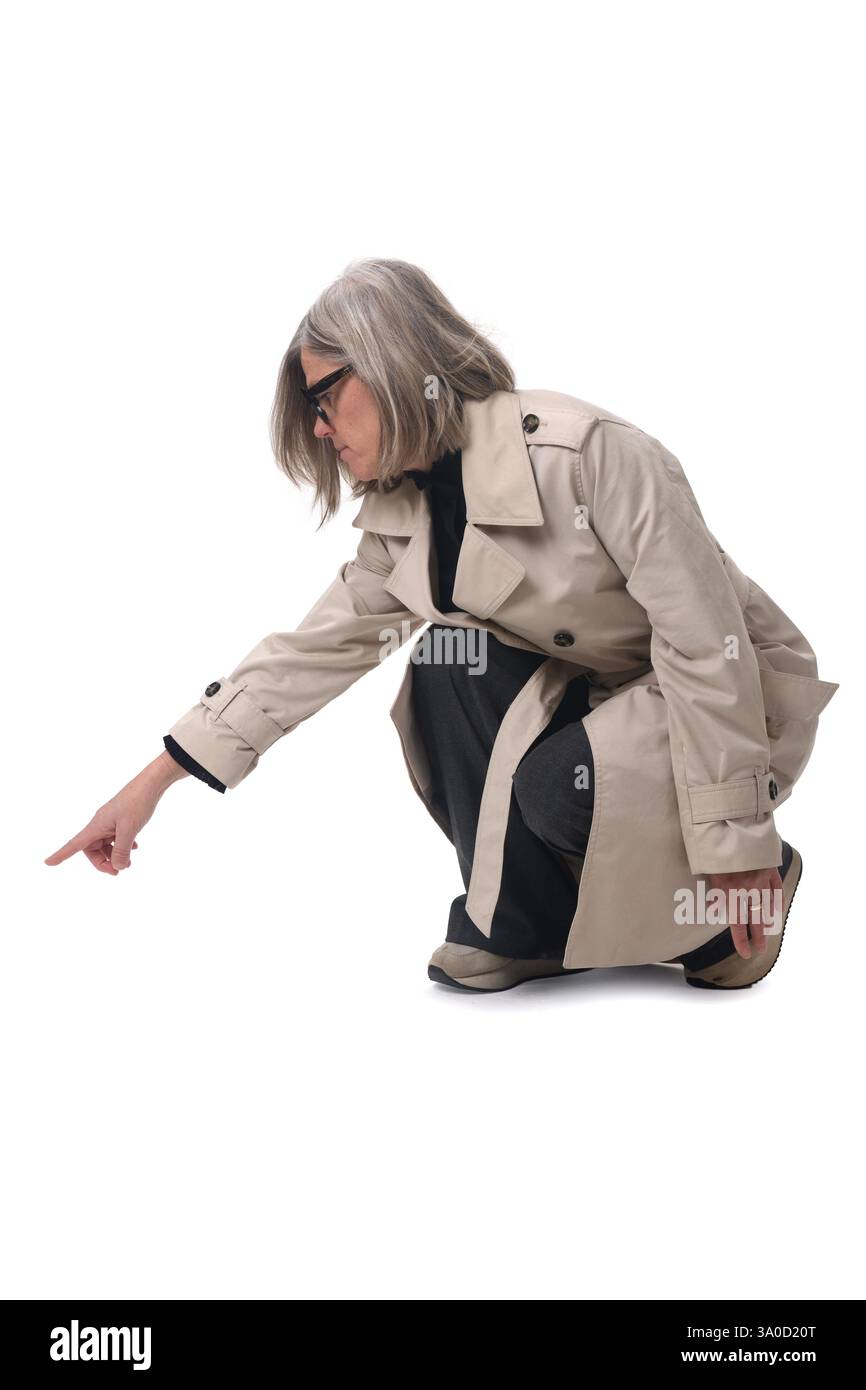 side view of a woman crouching and looking and pointing at the floor on ...