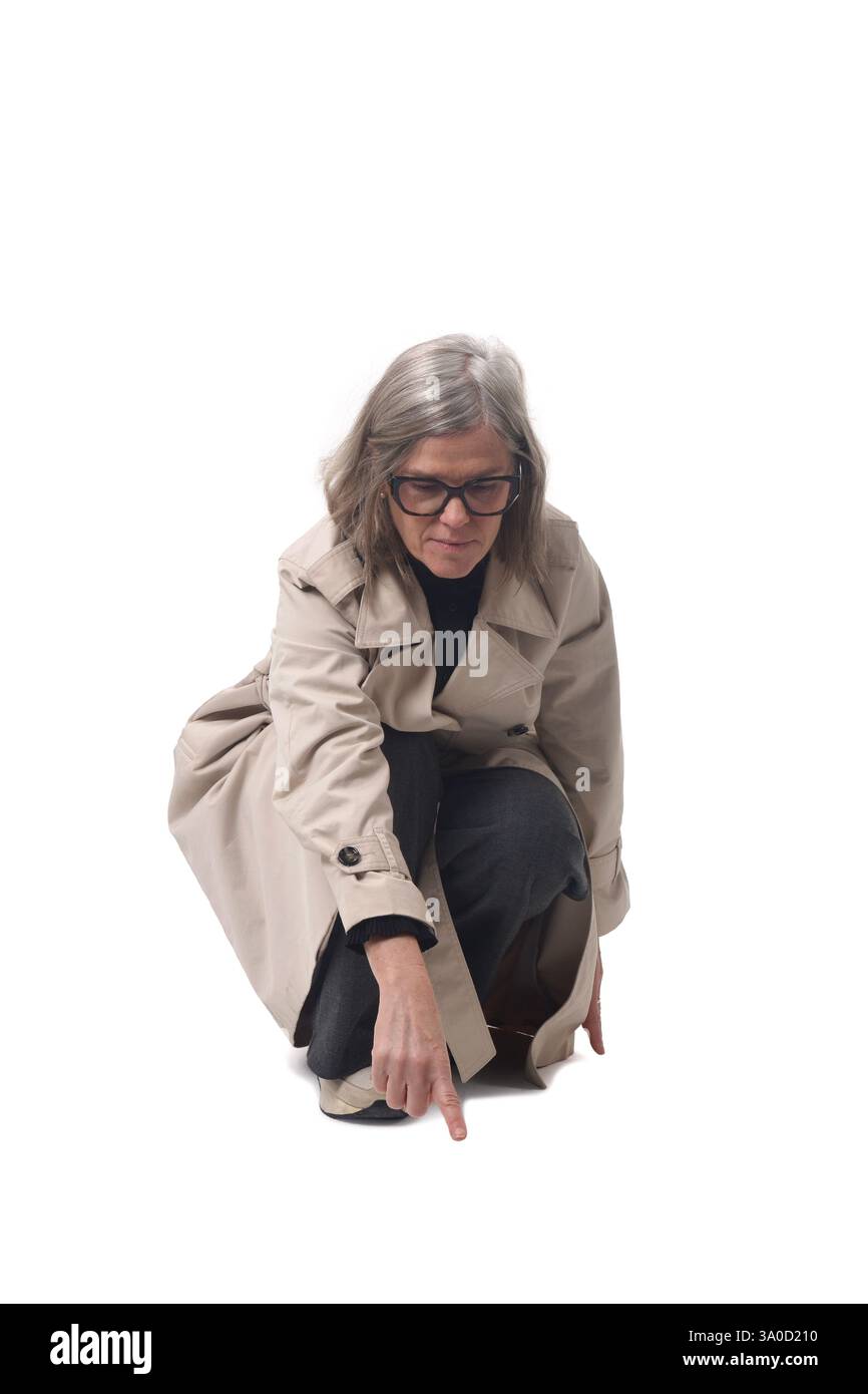 Front view of a woman crouching and looking and pointing at the floor ...