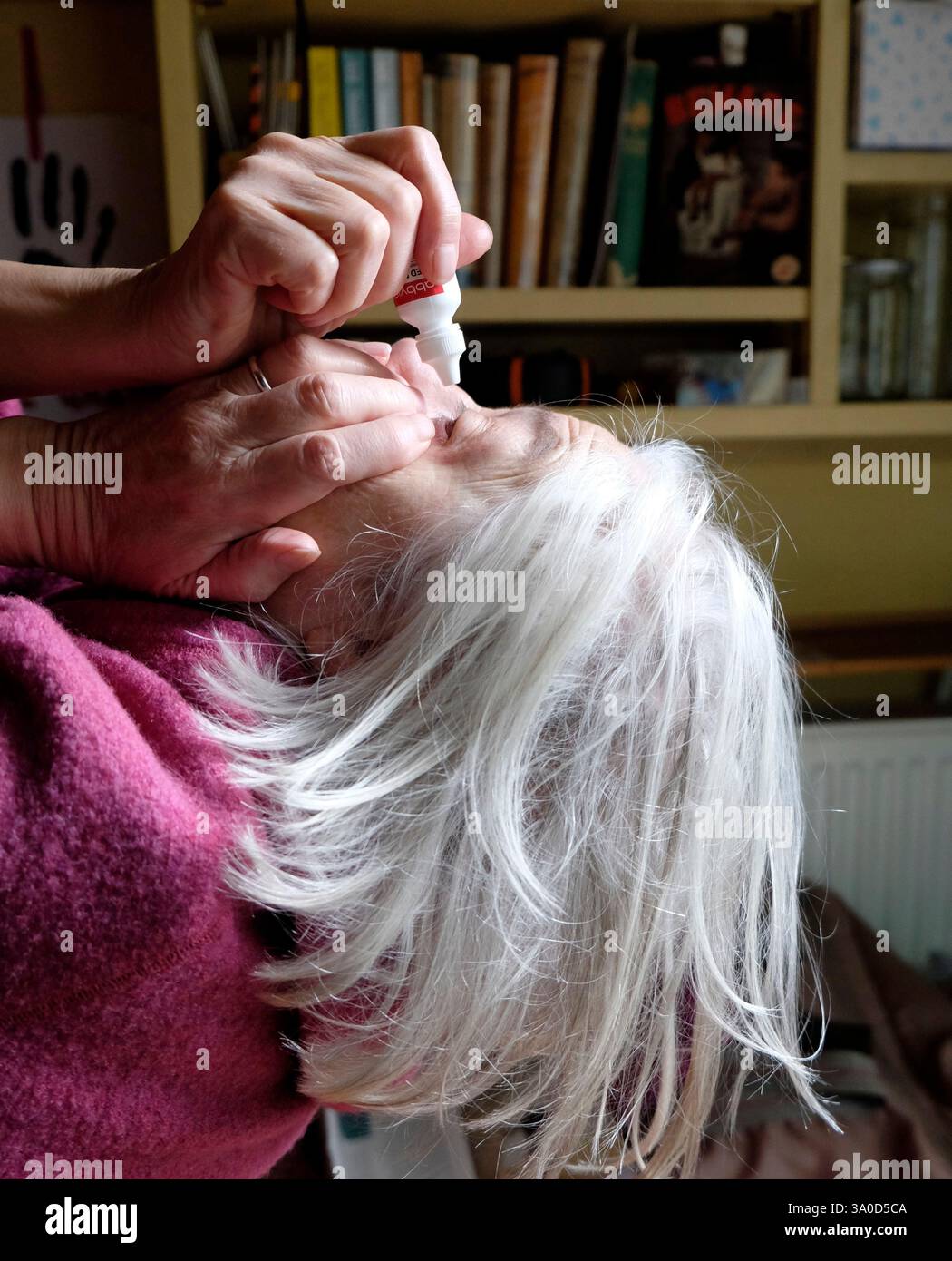 Older elderly woman grey white hair leaning back holding bottle of ...
