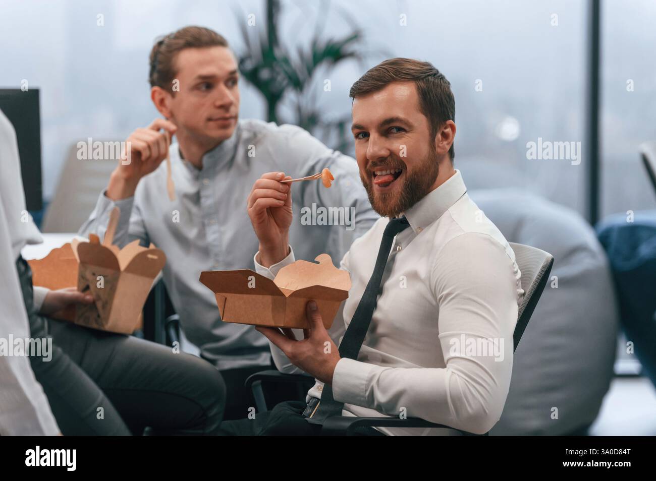 Coworkers are sitting in the office and eating food from eco boxes ...