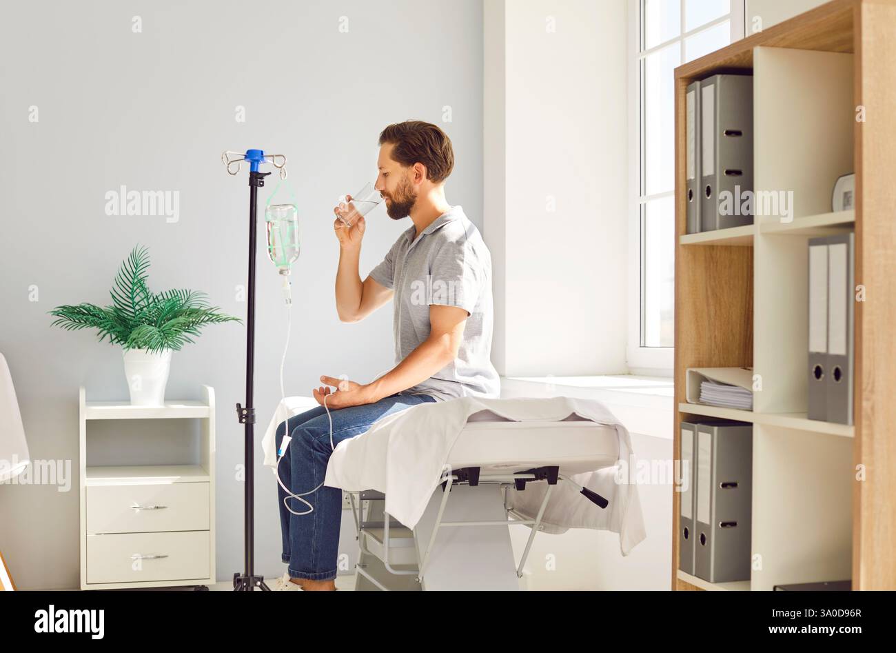 Dehydrated male patient drinks water while receiving intravenous ...