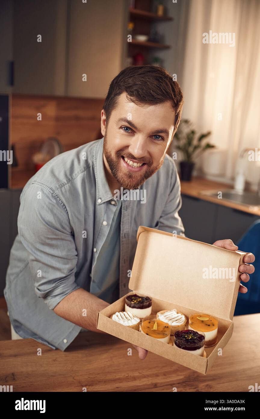 Smiling, showing sweets. Man is with delicious desserts that are in the ...