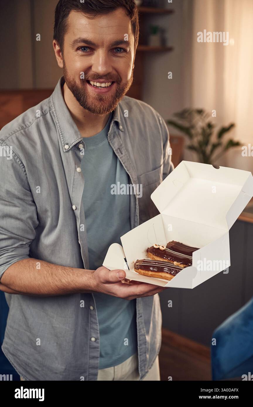 Smiling, showing sweets. Man is with delicious desserts that are in the ...