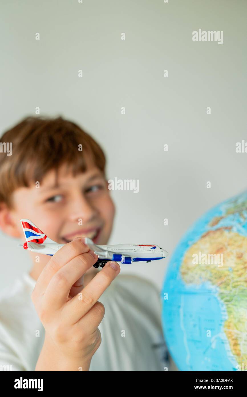 Little cute boy is looking at the globe with small airplane in his ...