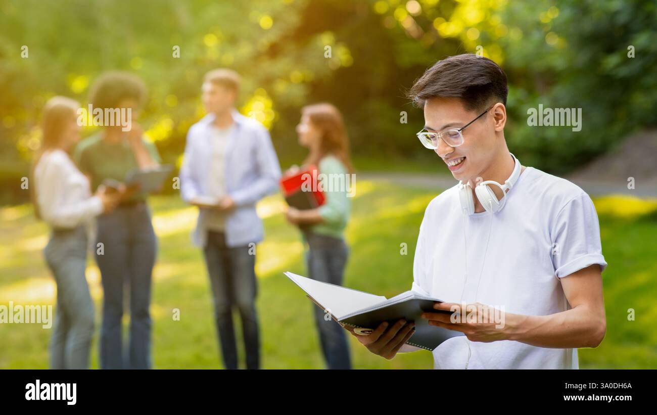 Happy Chinese Male Student Resting At Campus After Classes, Holding ...