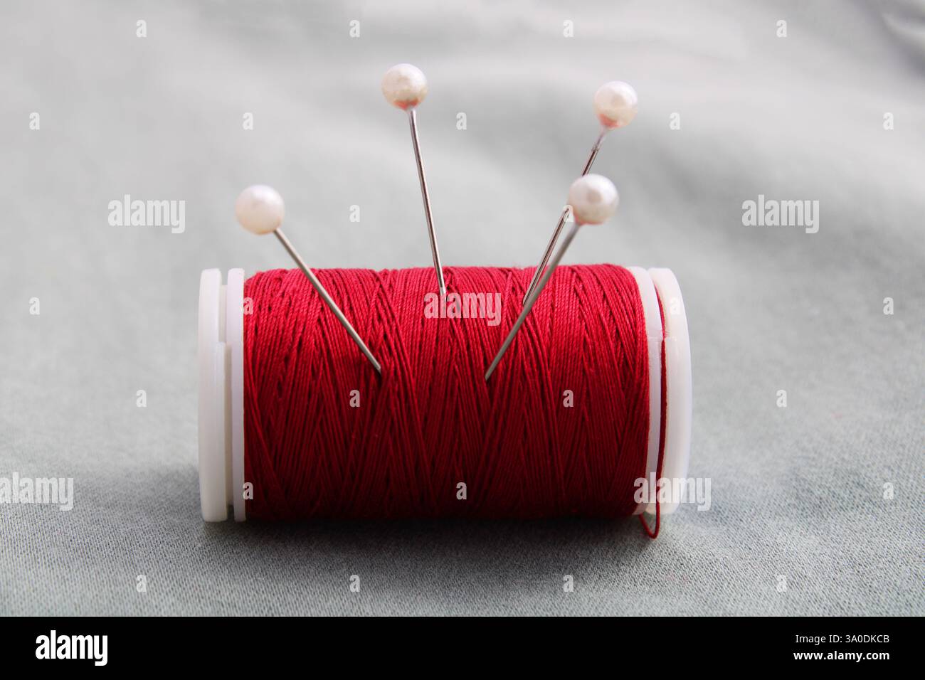 Sewing pins on a spool of red thread Stock Photo - Alamy