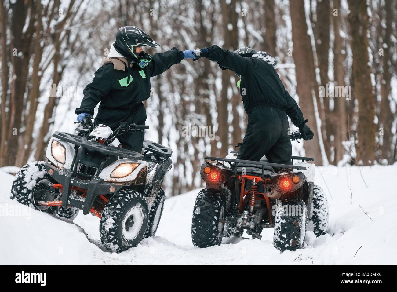 Making gestures. Two people are riding ATV in the winter forest Stock ...