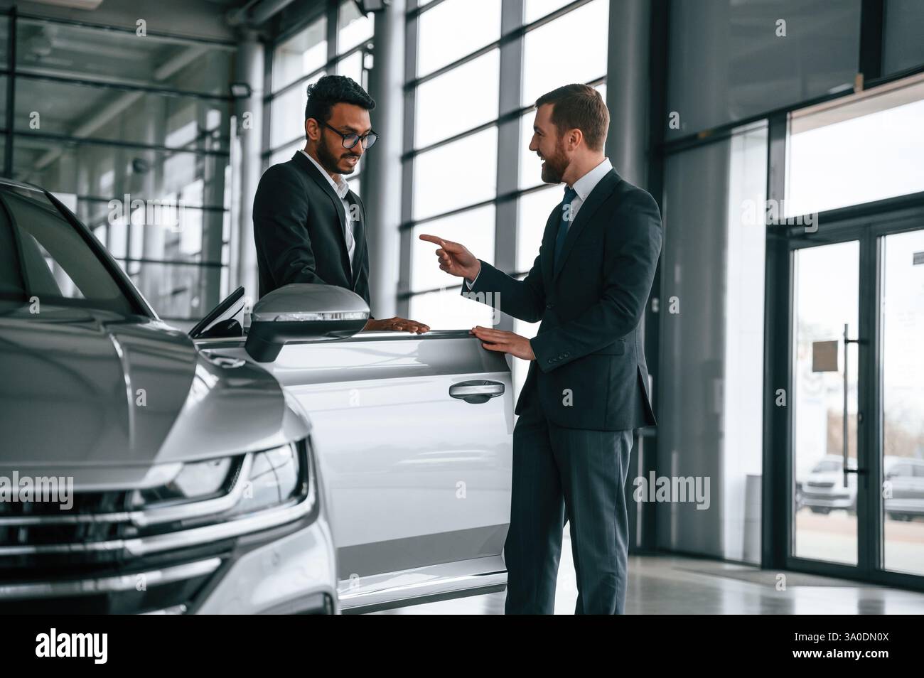 Business partners. Man is consulting the customer in the car showroom ...