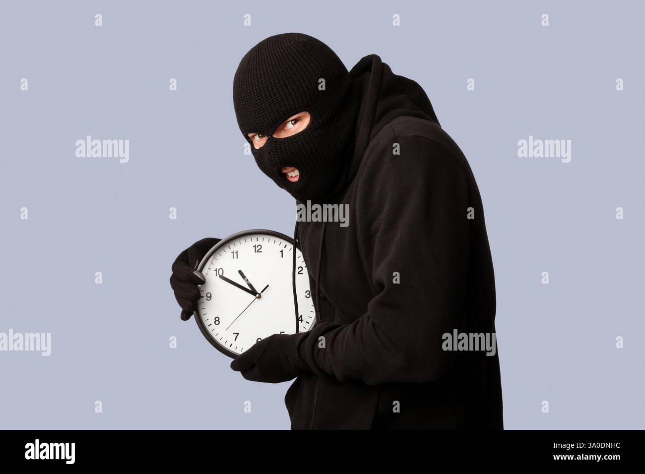 Portrait of masked thief with clock isolated over white wall Stock ...