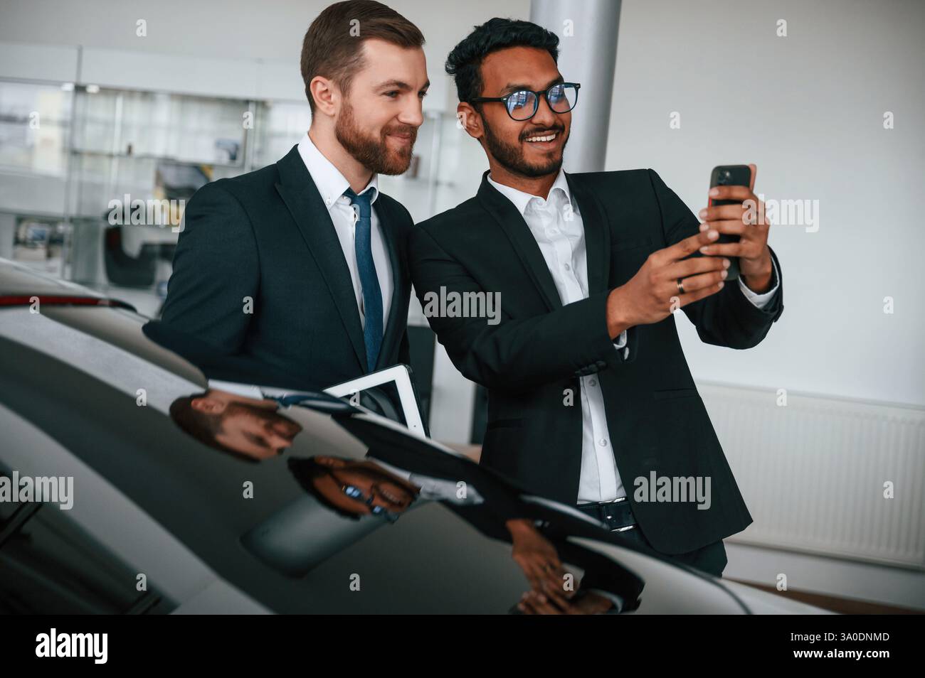 Having fun, using smartphone. Two businessmen are working together in ...