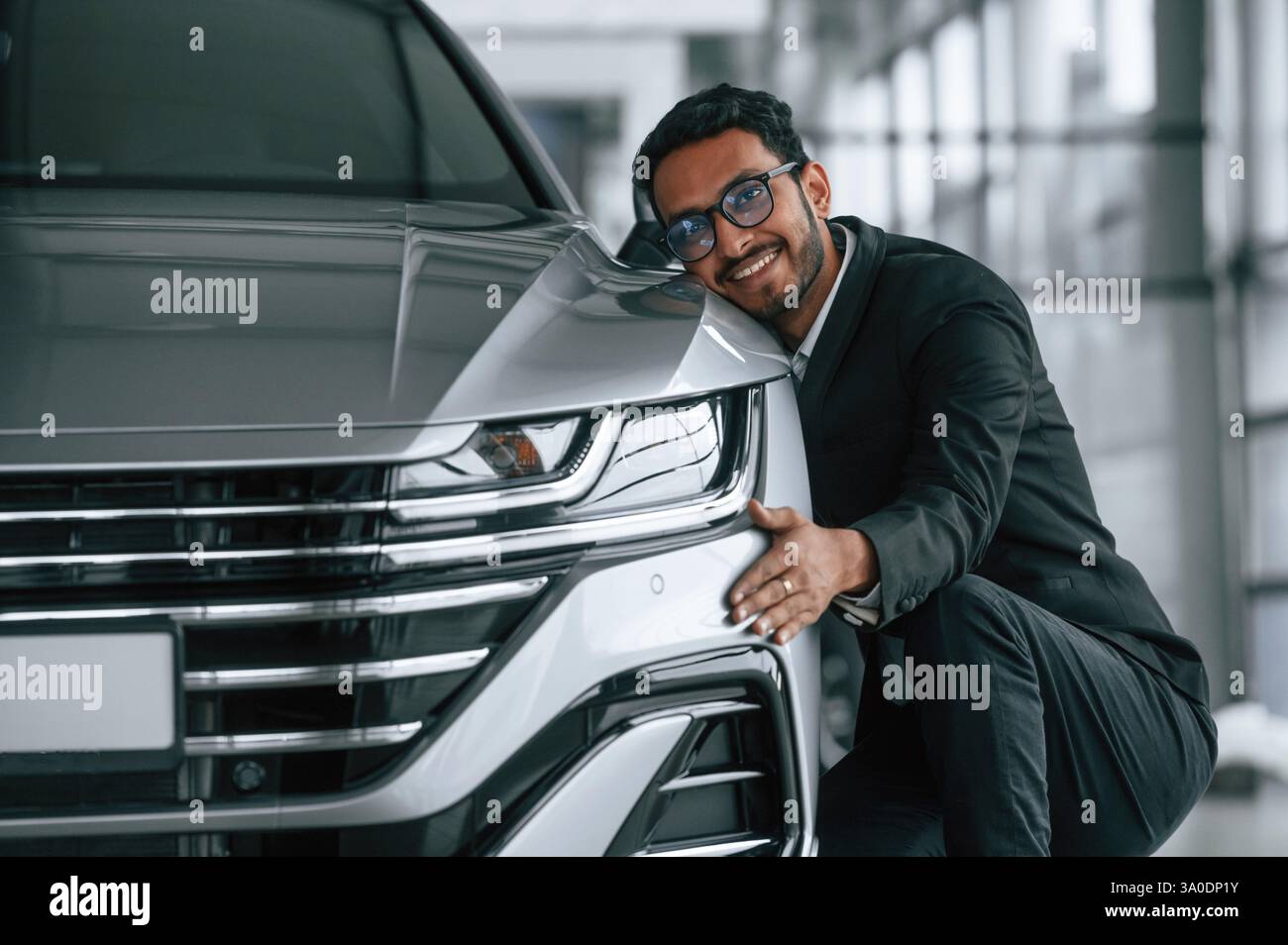 Embracing the transport. Handsome indian man in suit is in the car ...