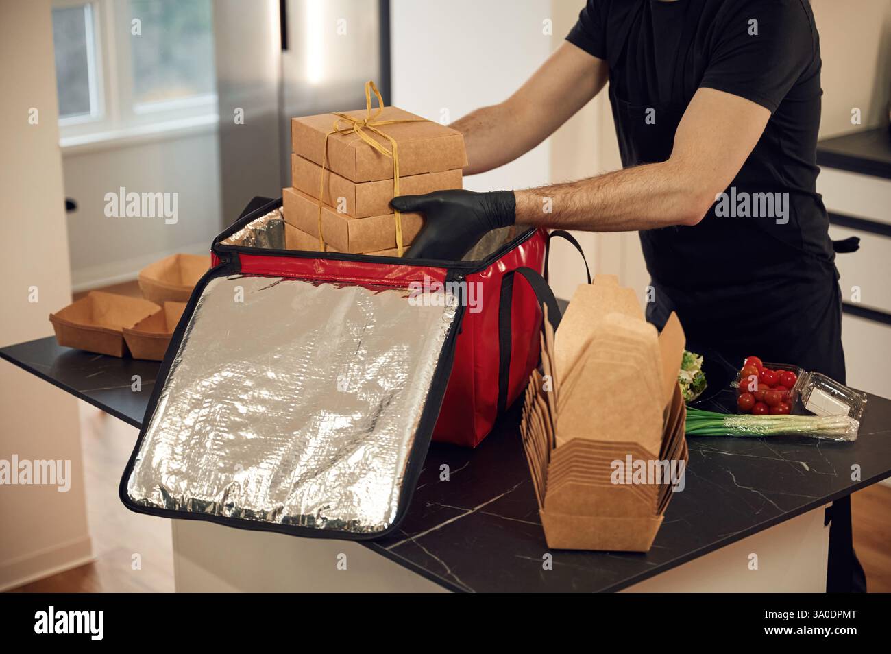 Man packs paper eco boxes into a bag for food delivery Stock Photo - Alamy