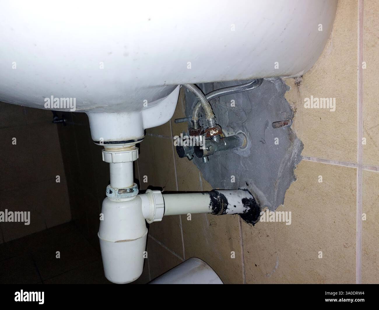 A close-up view of plumbing components beneath a sink shows the ...