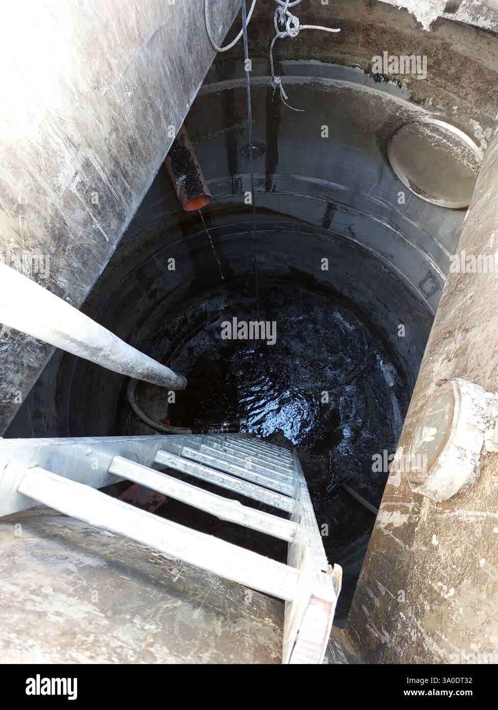 A sturdy ladder descends into the dark depths of a sewer well ...