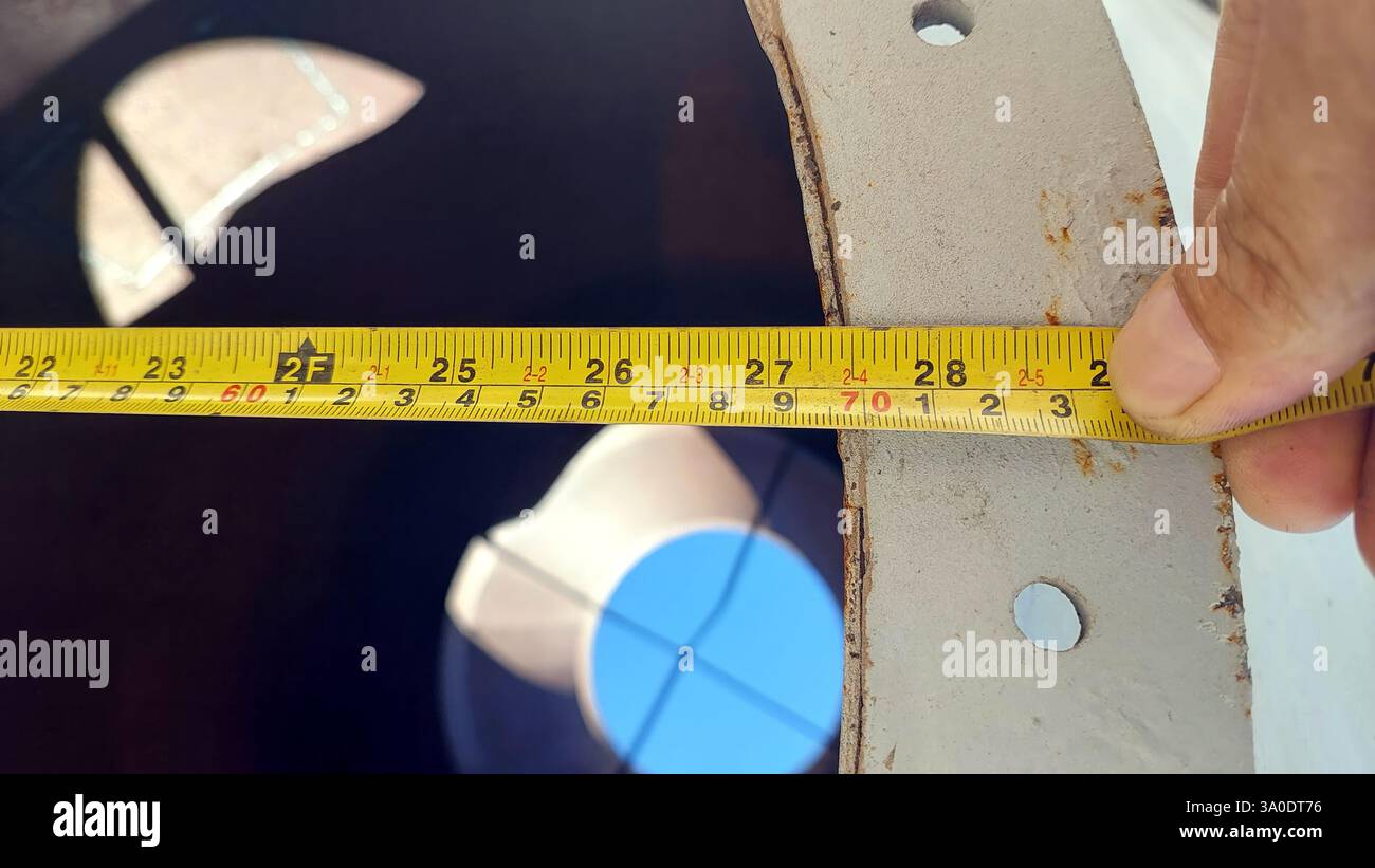 A close-up view captures a hand holding a tape measure against the edge ...