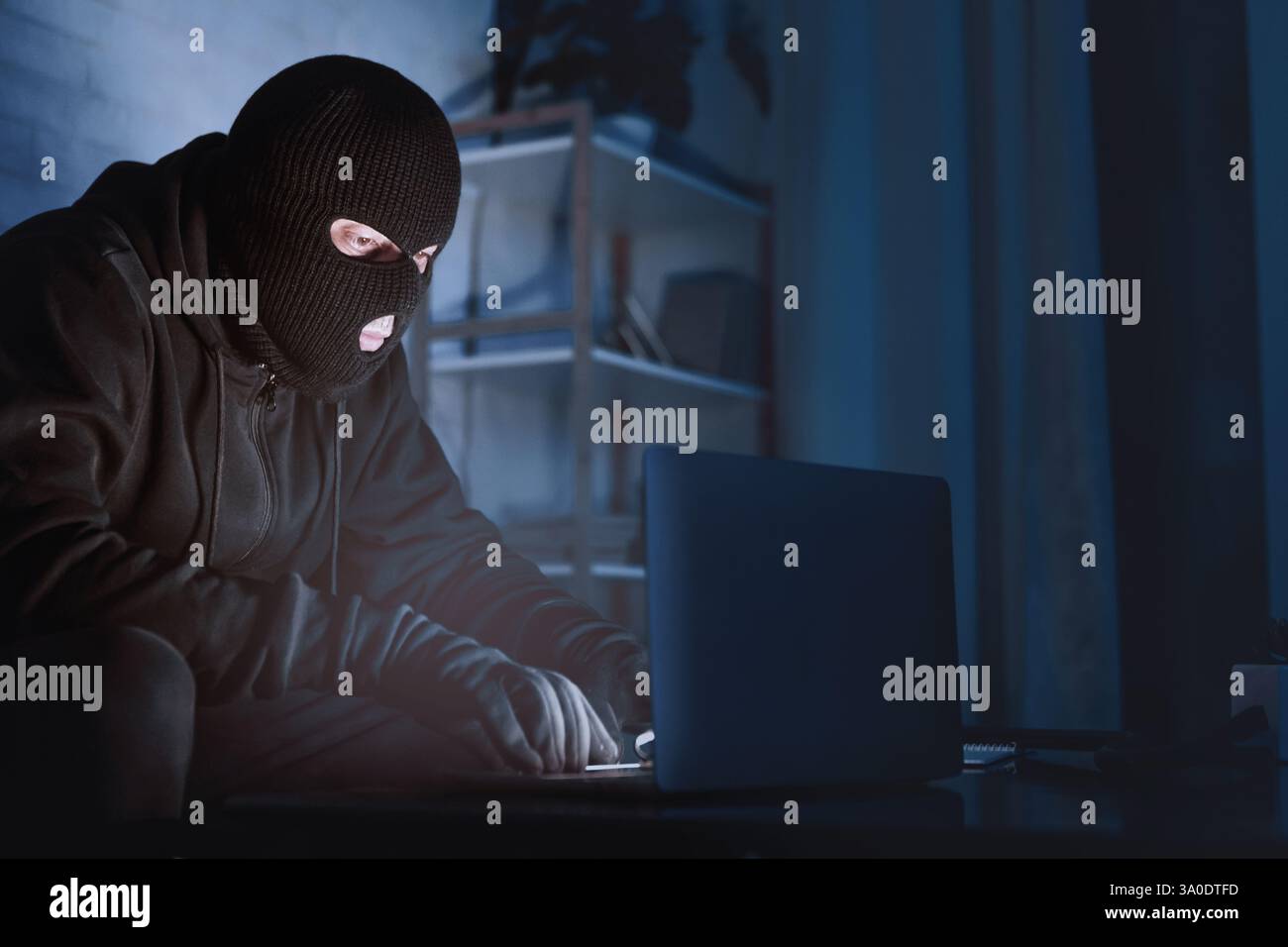 Masked hacker downloading private information using pc Stock Photo - Alamy
