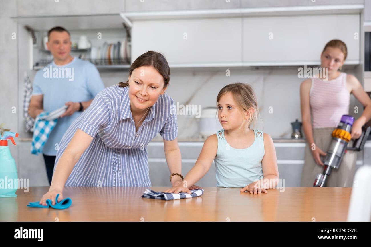 Smiling woman wiping kitchen table with tween daughter Stock Photo - Alamy