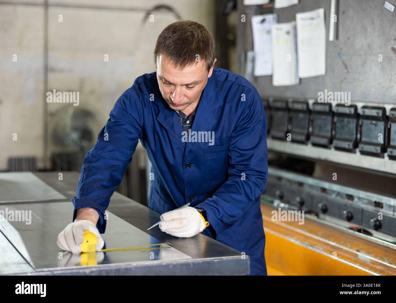 Man measuring sheet of metal with tape measure Stock Photo - Alamy