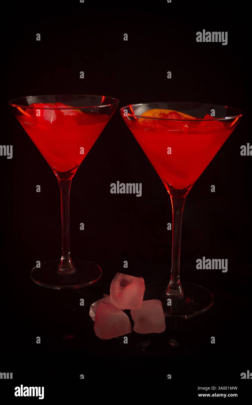 Cocktails frais avec glaçons rouge orange disposés sur fond noir avec ...