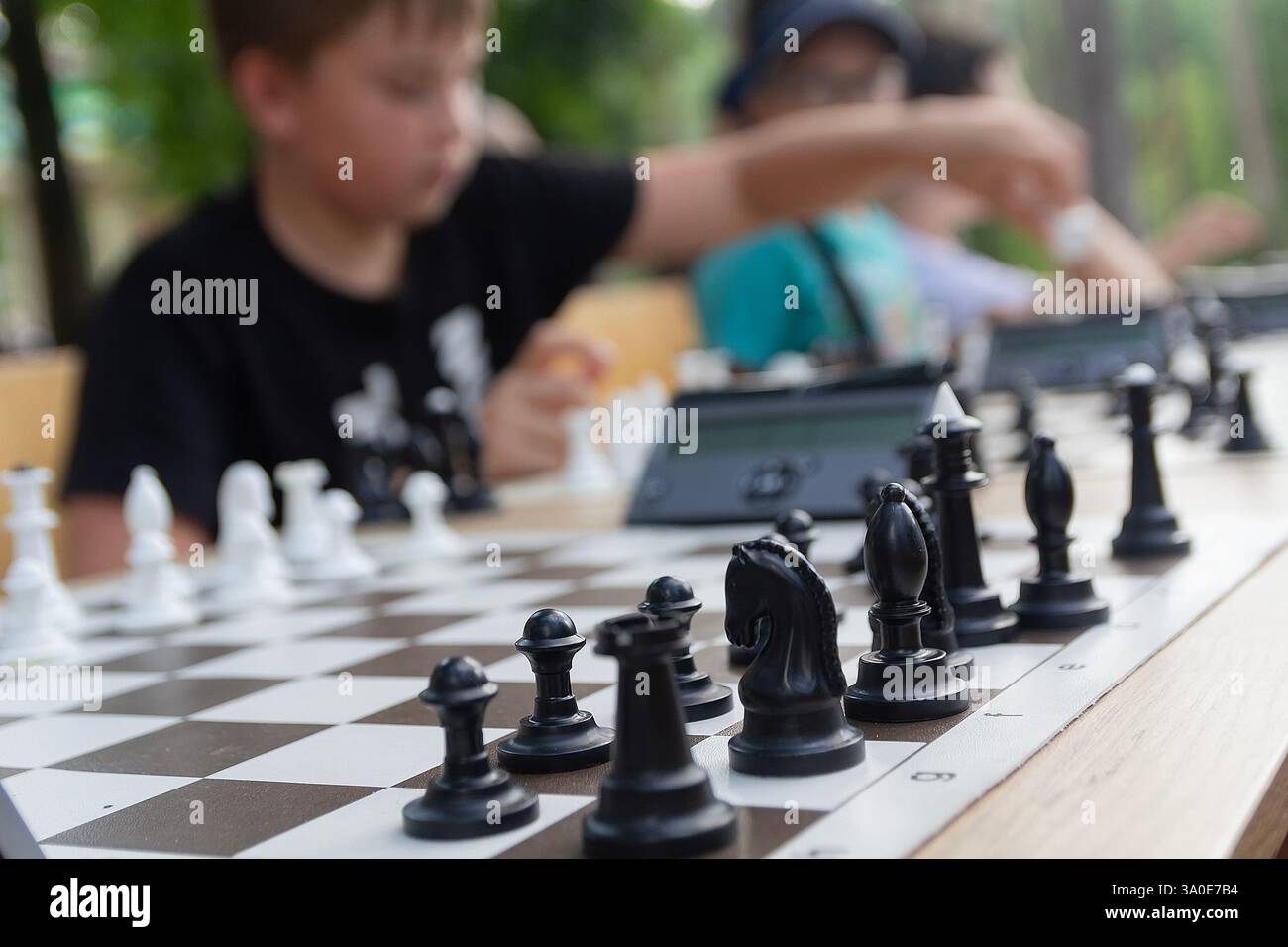 A child's hand makes a move during a chess tournament. Several chess ...