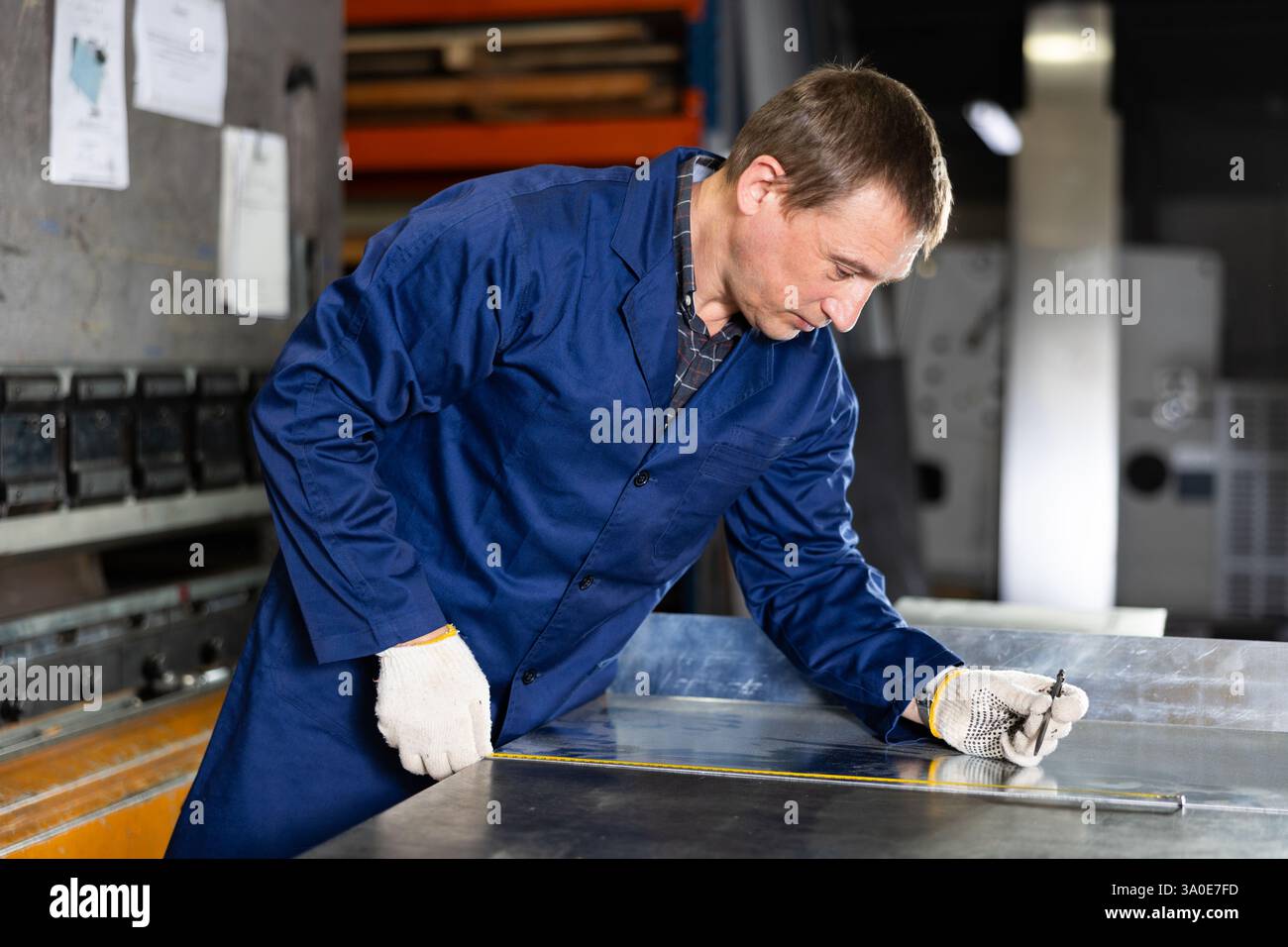 Man measuring sheet of metal with tape measure Stock Photo - Alamy