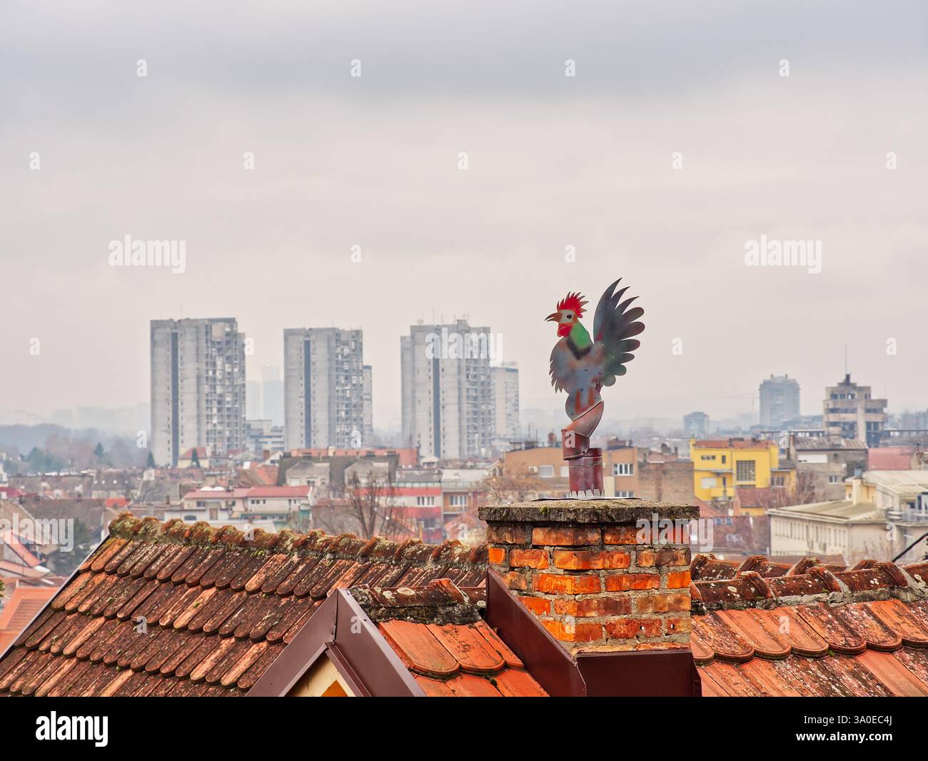 Colorful rooster statue atop brick chimney, overlooking city with high ...