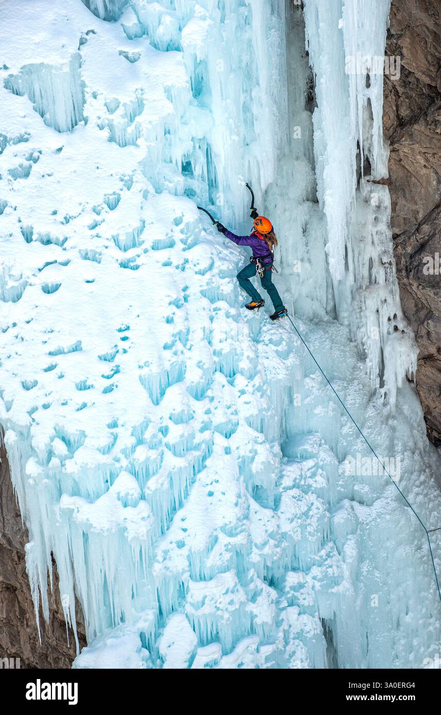 A single adult woman ice climbing in Ouray ice Park in the San Juan ...