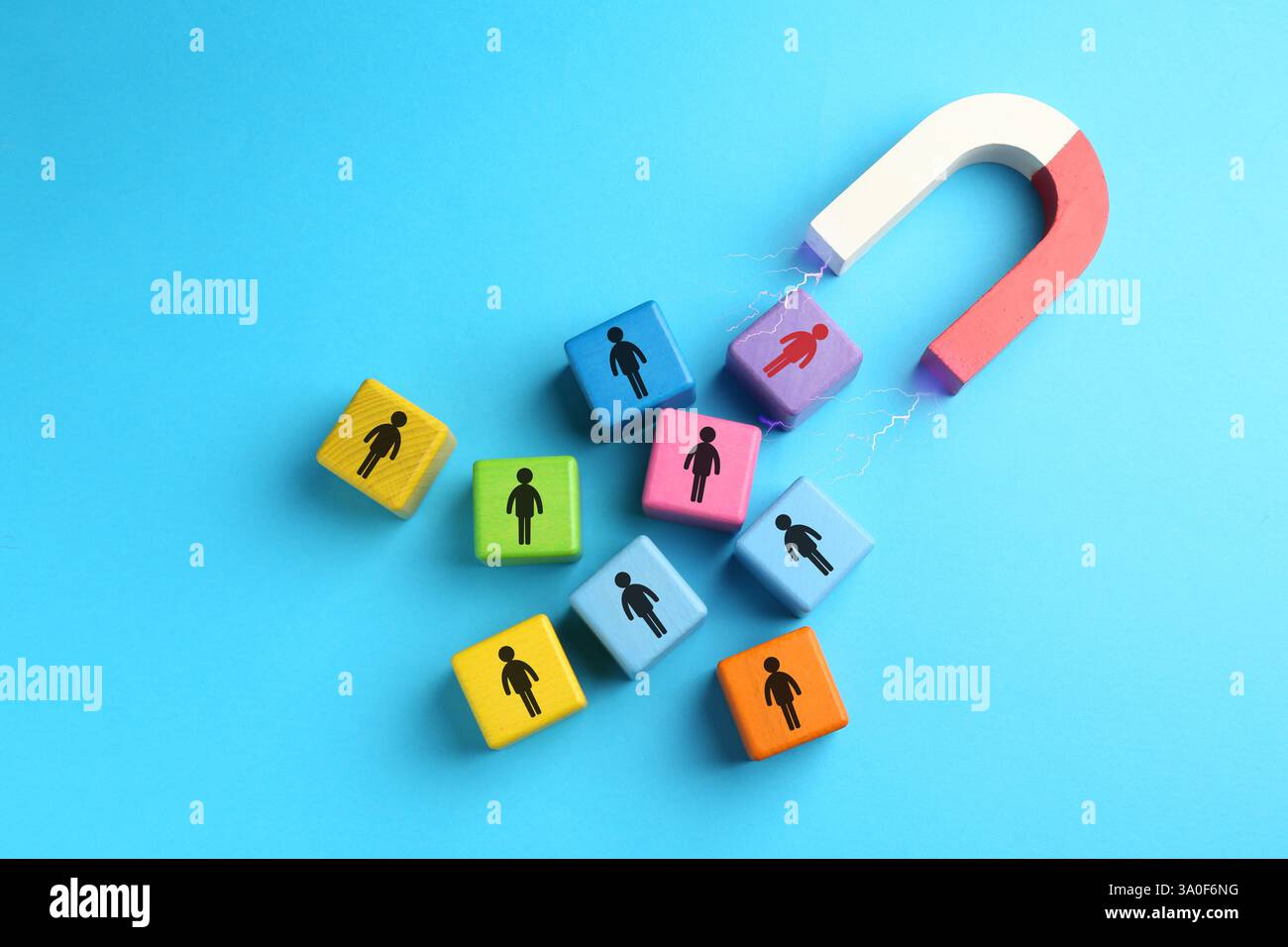 Magnet attracting colorful cubes with human figures on light blue ...