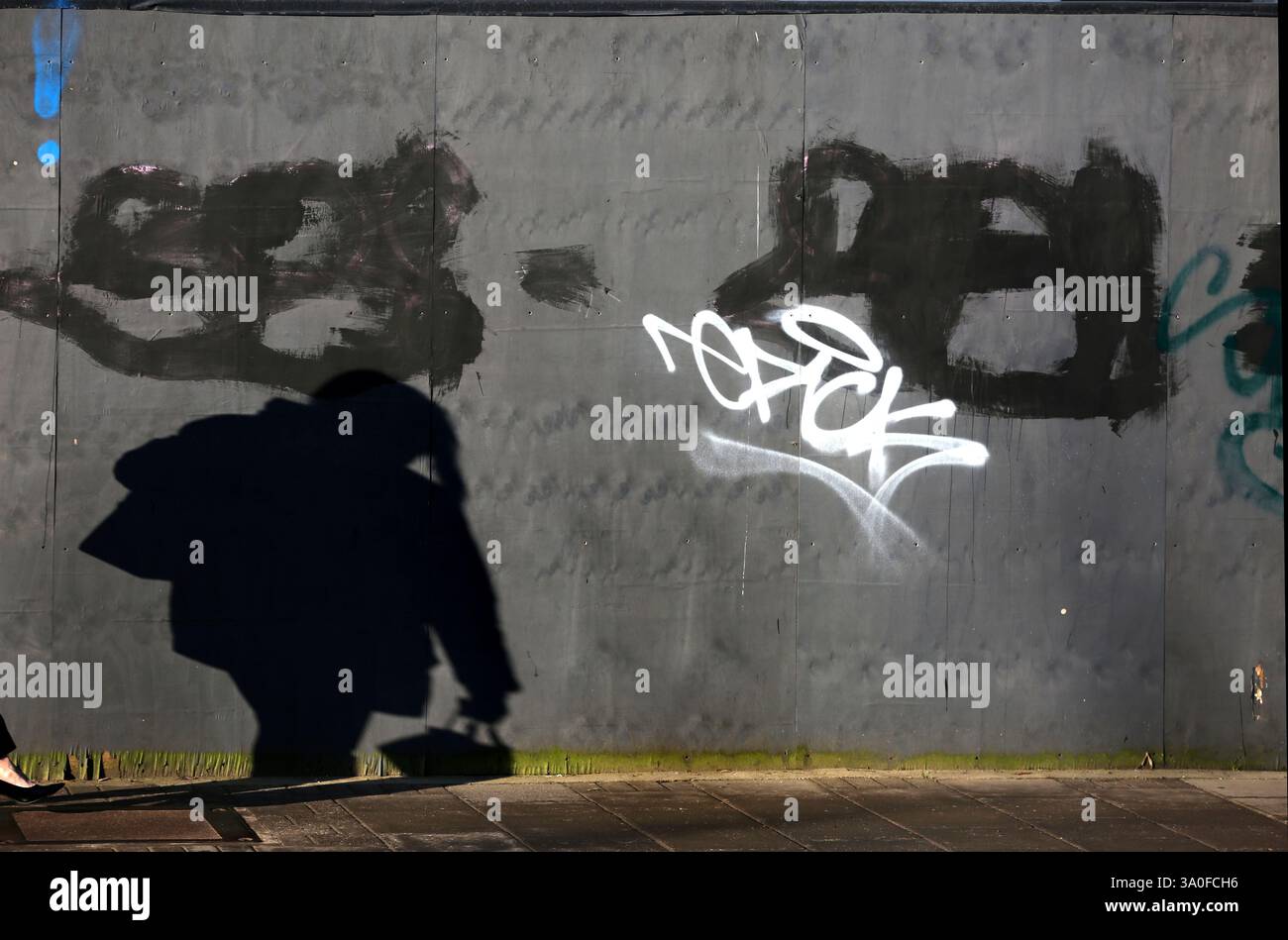 A commuter’s shadow is projected onto construction site hoardings in ...