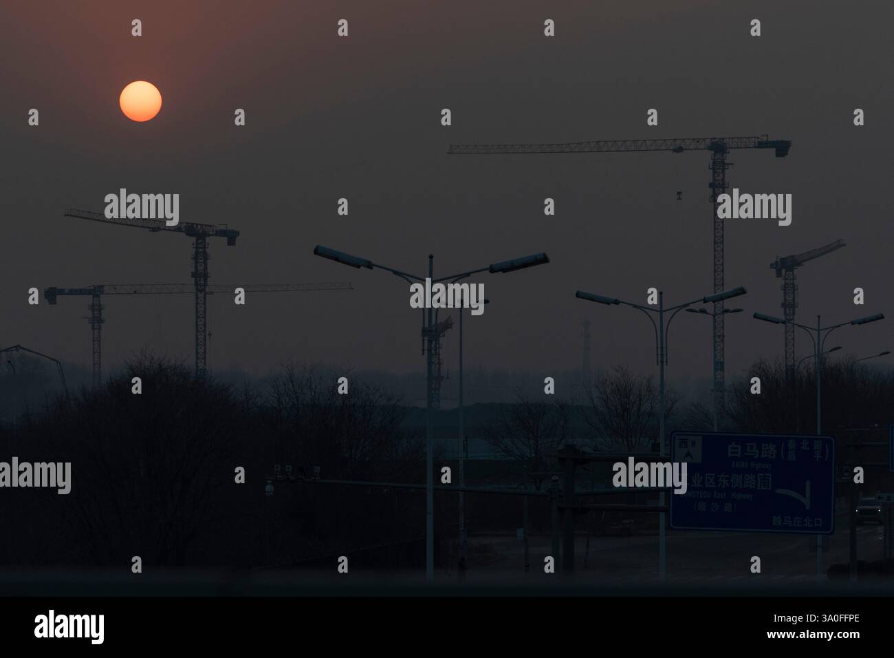Construction cranes are seen as the sun sets in Beijing, on Feb. 27 ...