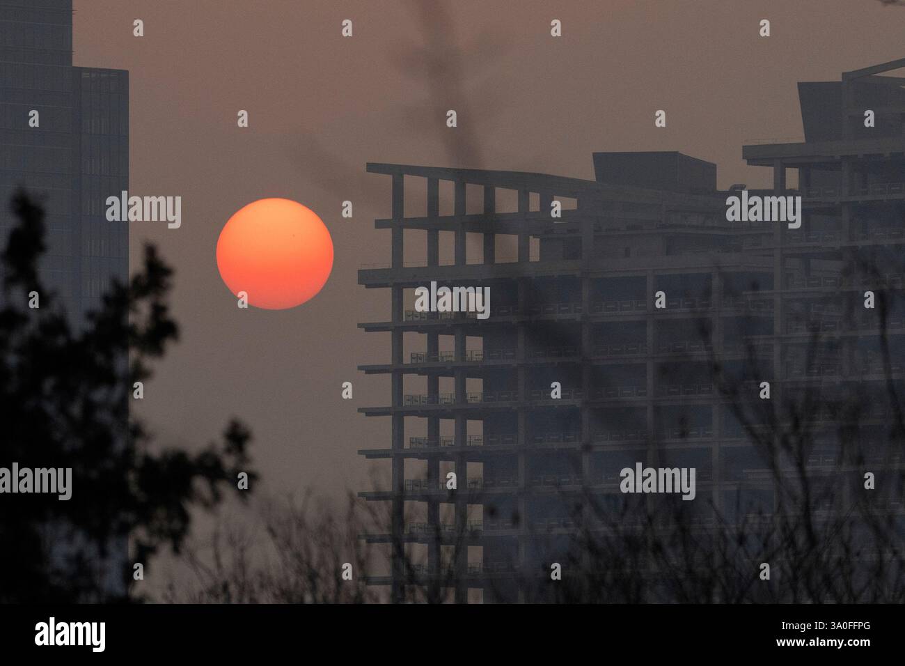 The sun sets near a partially constructed building in Beijing, on Feb ...
