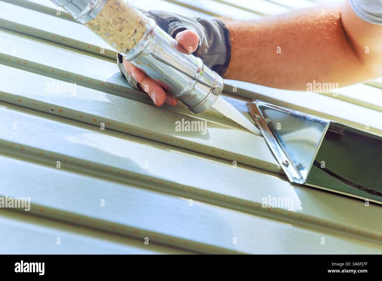 Contractor is sealing metal siding with caulk gun in home renovation ...