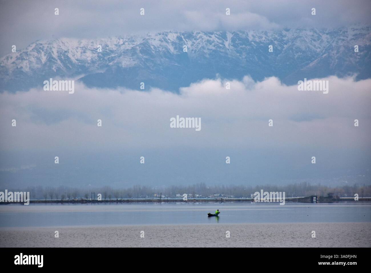 A boatman rows his boat as clouds engulf snow covered mountains after ...