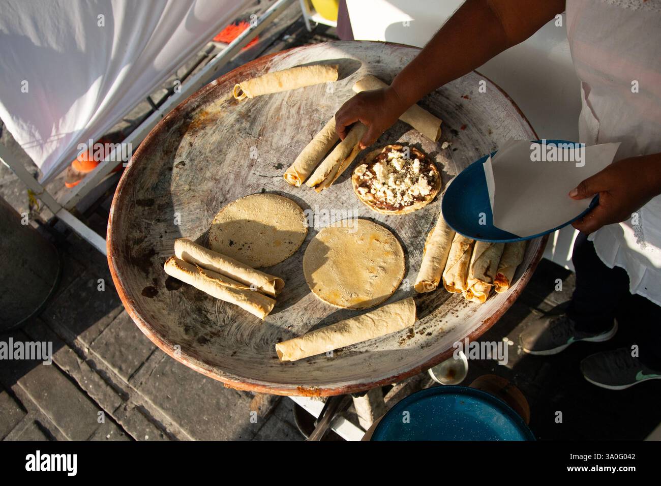A woman cooking tortillas, flautillas and Mexican memelas on a comal on ...