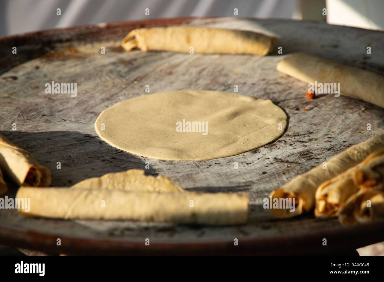 A woman cooking tortillas, flautillas and Mexican memelas on a comal on ...